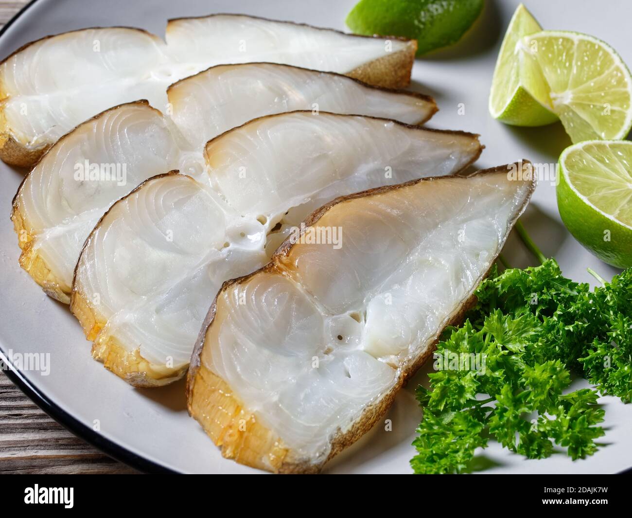 halibut fish slices served with lime on a plate on a rustic wooden ...
