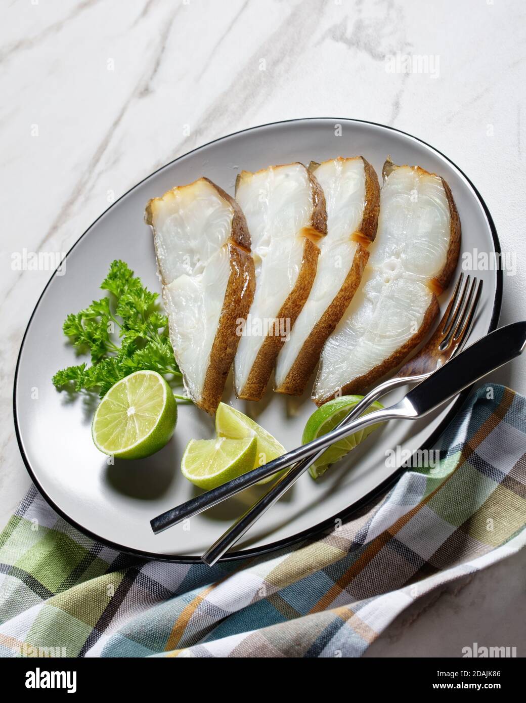 halibut fish slices served with lime on a plate on a marble table ...