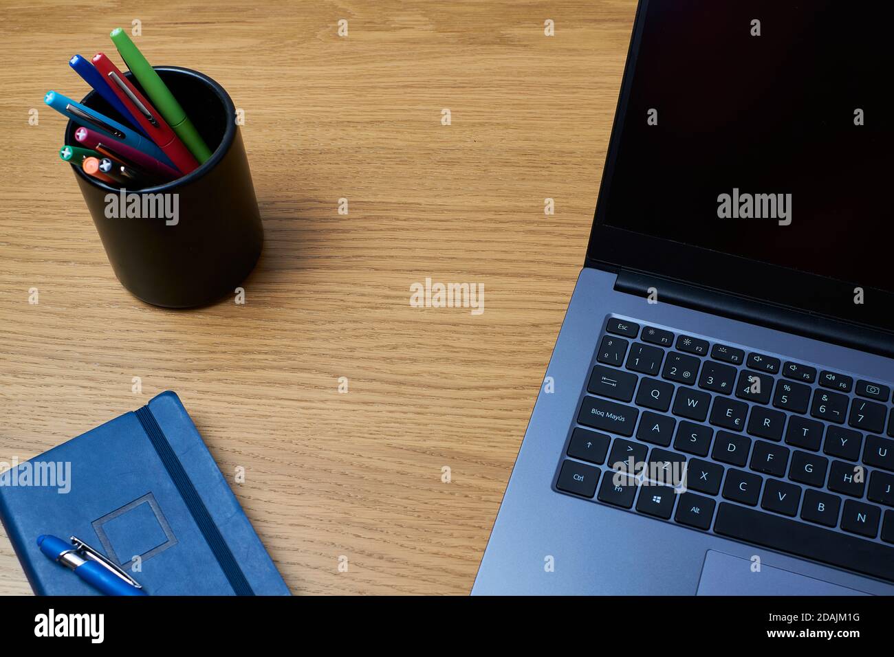 Closeup shot of a pen on a journal, pen box, and laptop on a wooden ...