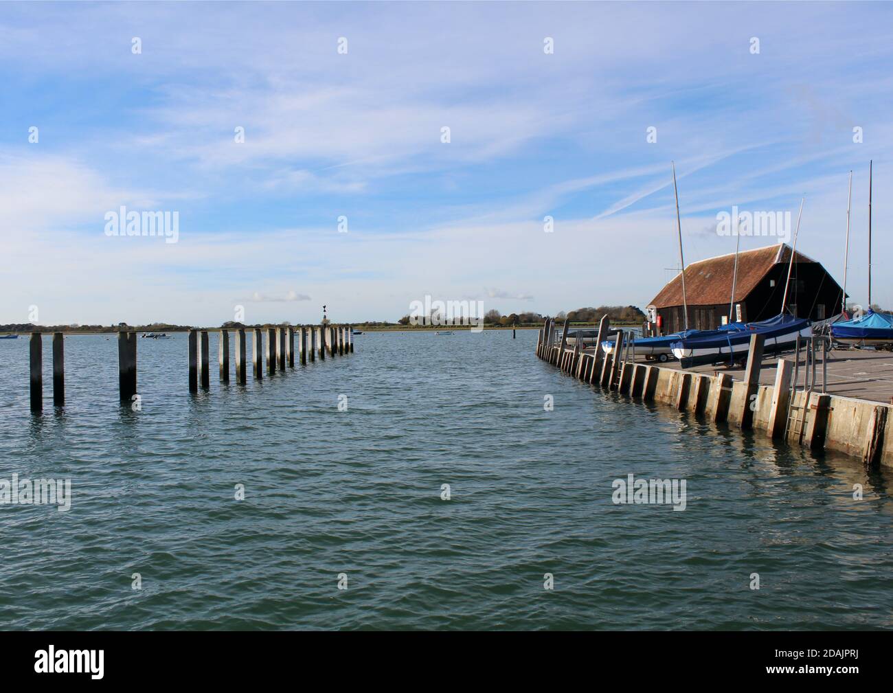 Bosham Quay looking out to far shoreline between mooring posts and quay ...