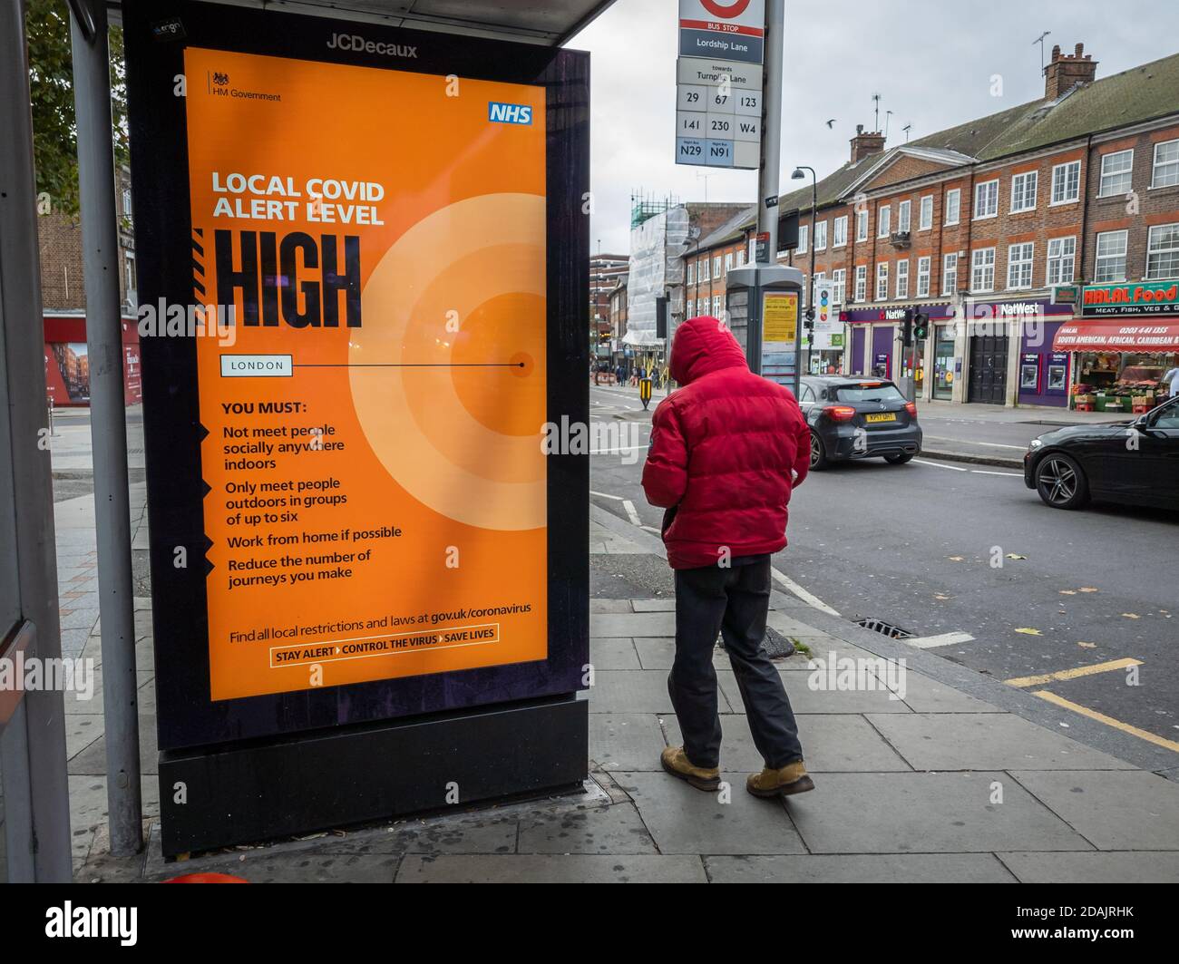 A local Covid-19 alert level sign by a bus stop on a London high street ...