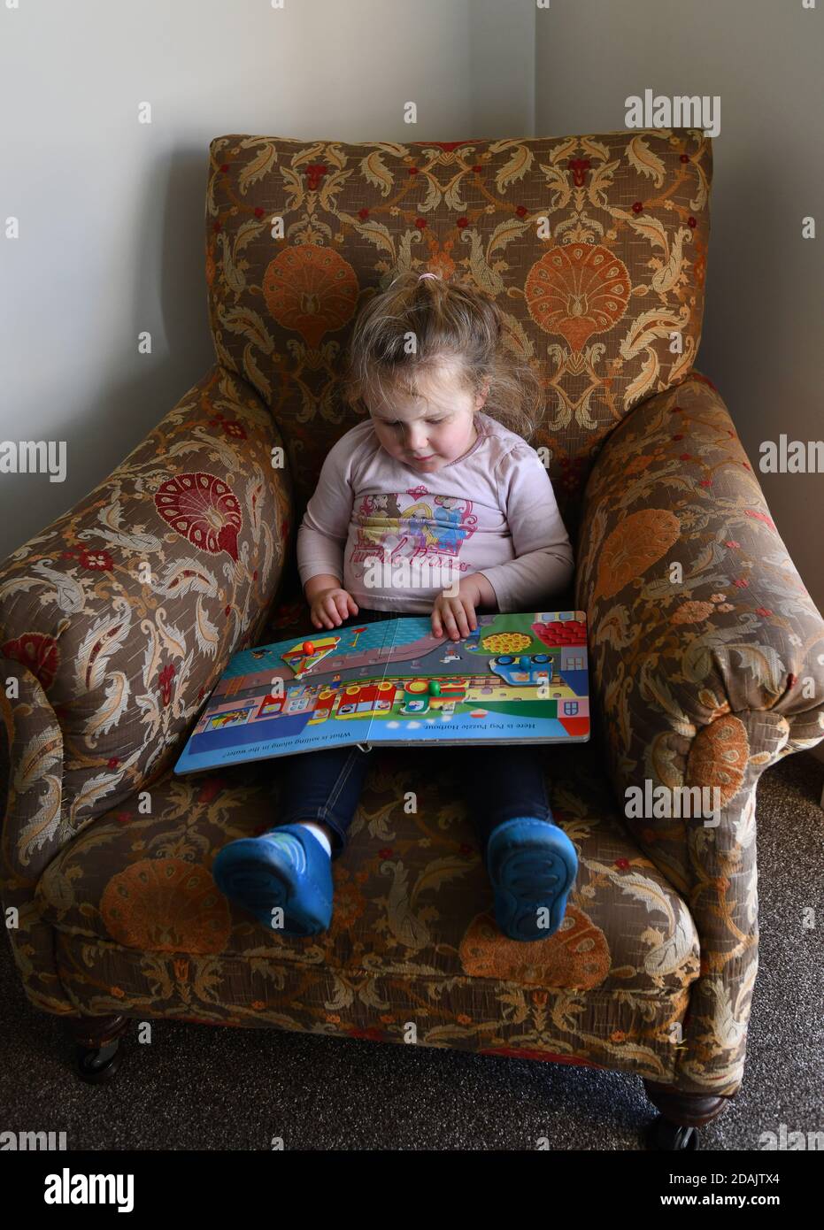 Cute child toddler girl looking at book Stock Photo - Alamy