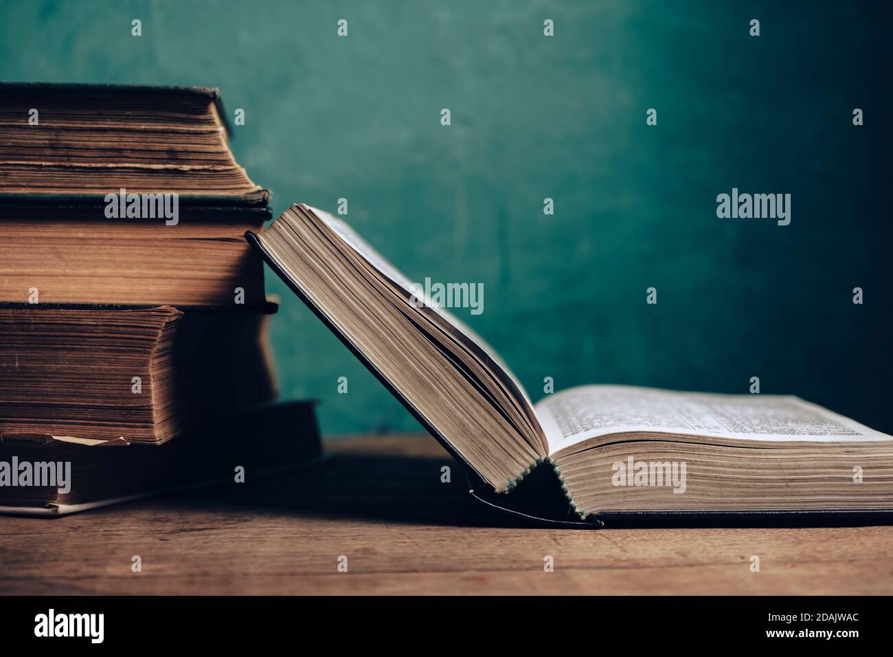 Beautiful open Holy Bible on a old brown oak wooden table. Green wall ...