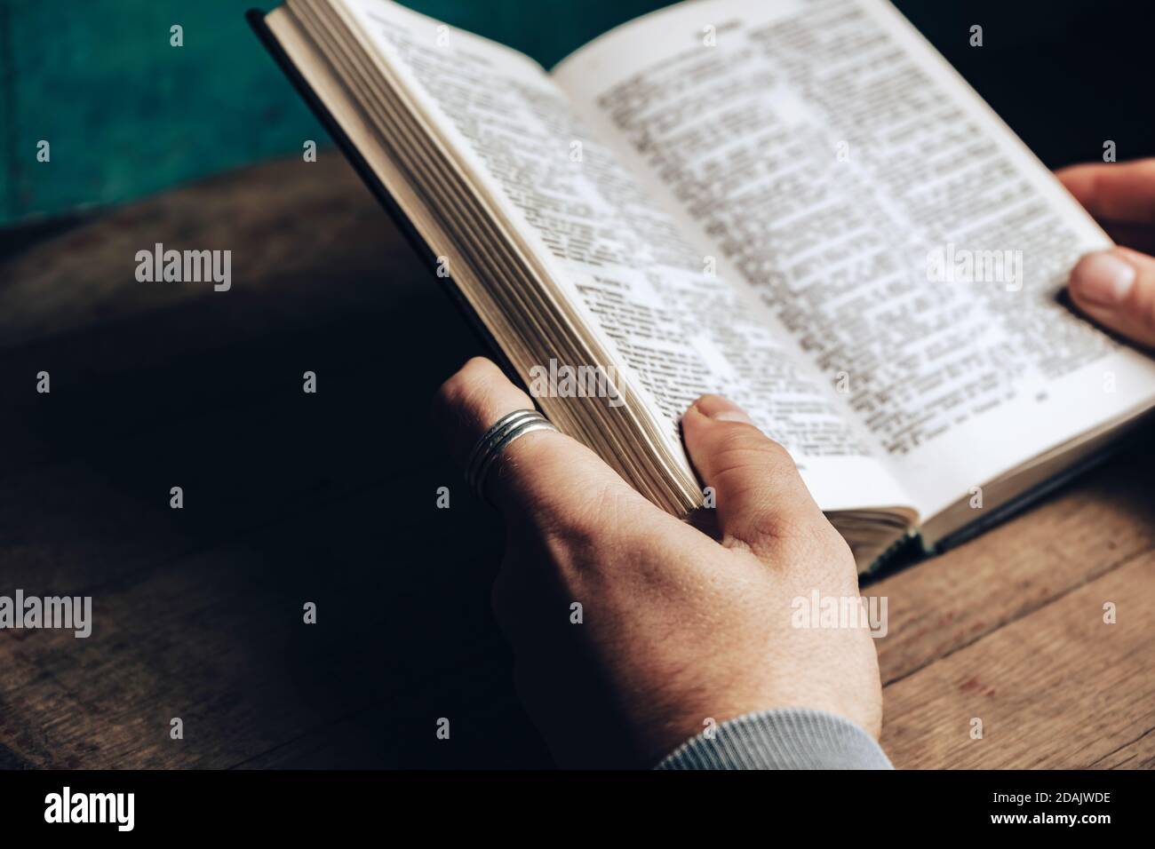 Man sitting at a reading the Holy Bible on a old oak wooden table and ...