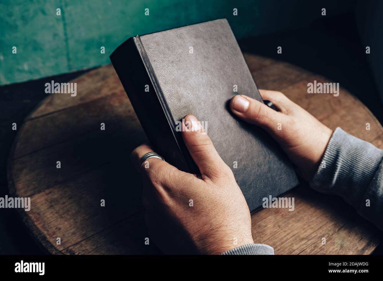 Man sitting at a reading the Holy Bible on a old oak wooden table and ...