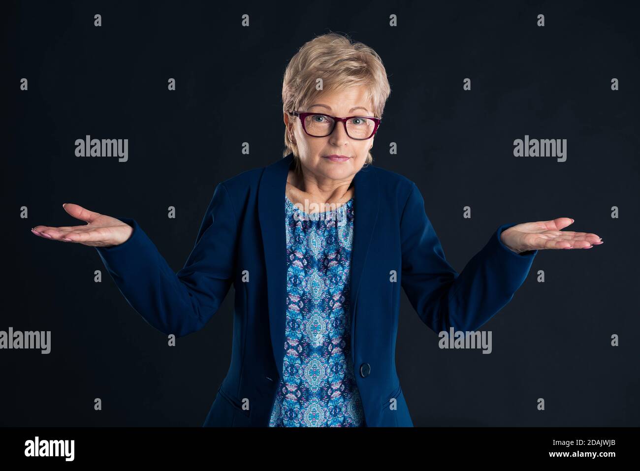 Senior businesswoman making I don't know sign wearing a blue jacket on ...
