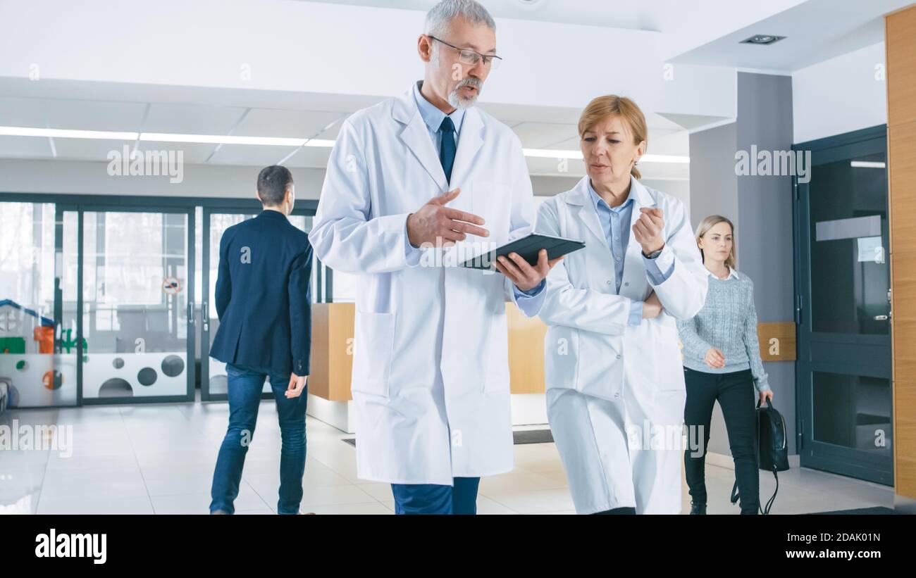 In the Hospital, Busy Doctors Talk, Using Tablet Computer While Walking ...