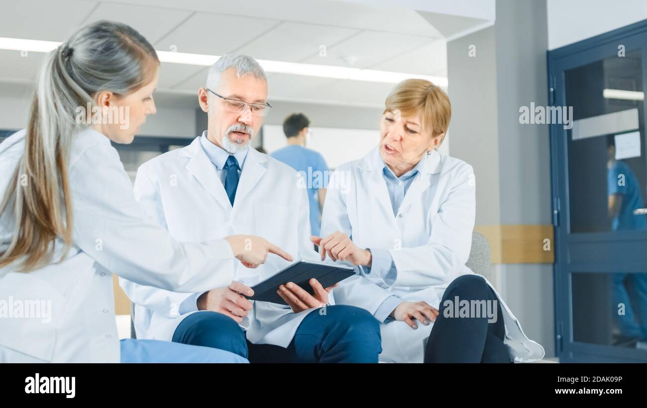 In the Lobby of the Hospital Three Professional Doctor Have Discussion ...