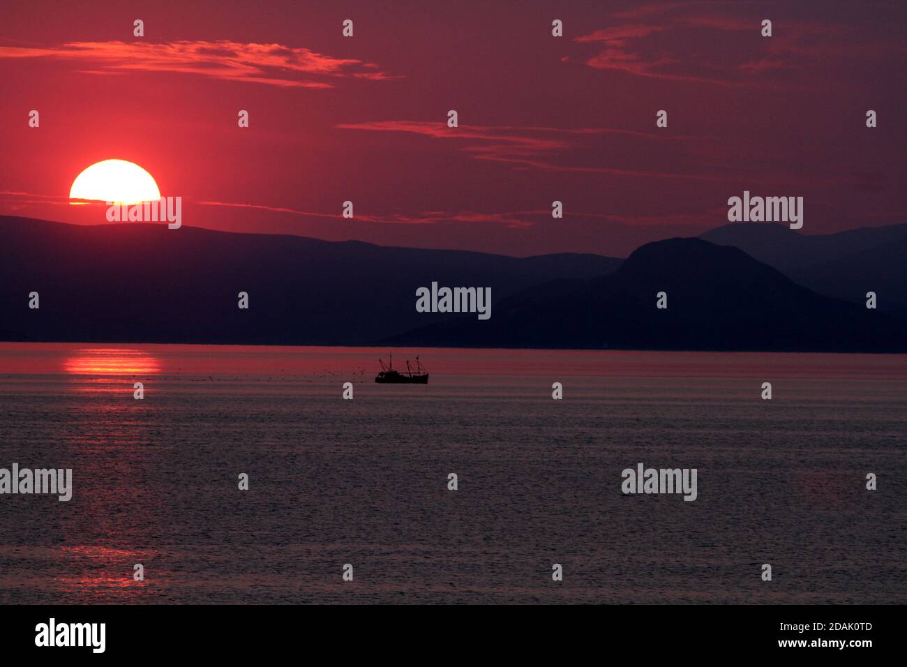 The sun set behind the Isle of Arran on the west coast of scotland, as ...