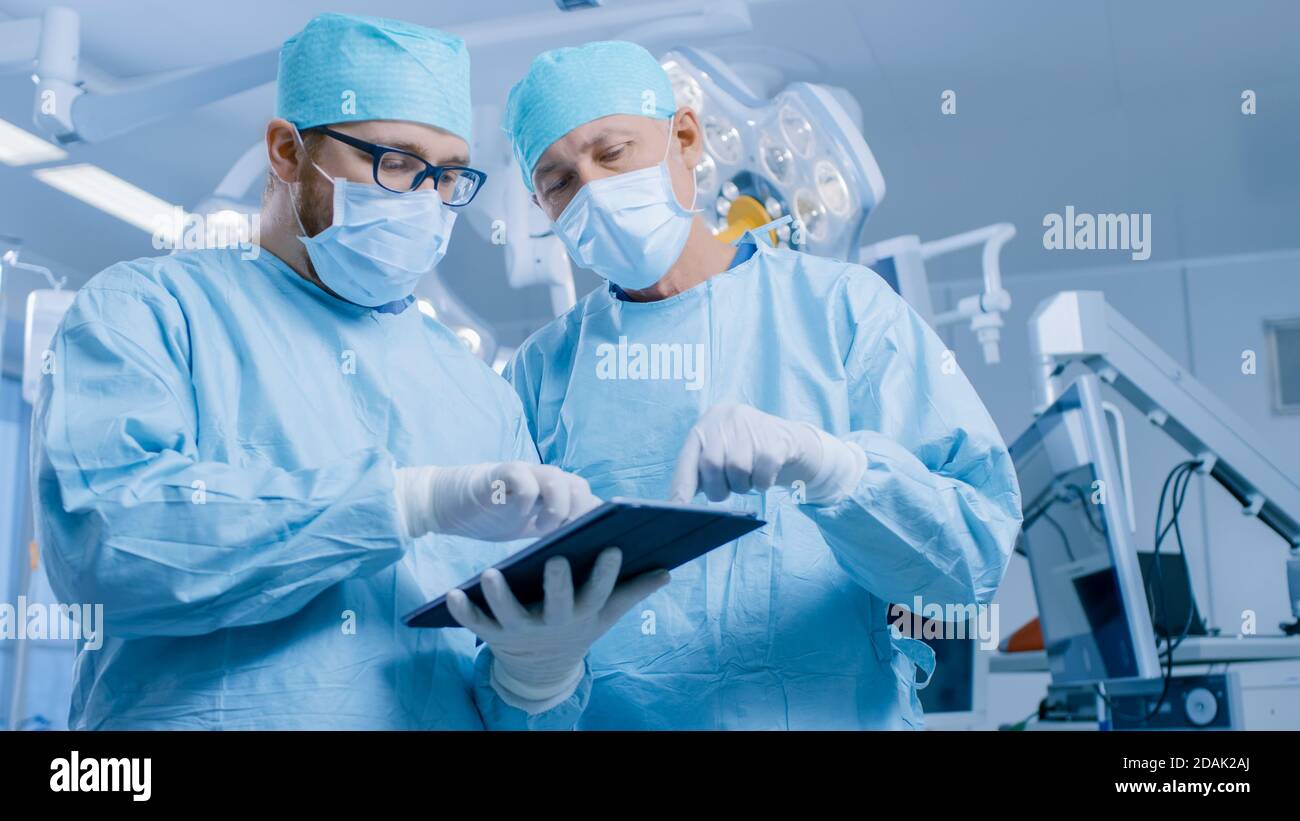 Two Professional Surgeons Use Digital Tablet Computer while Standing in ...