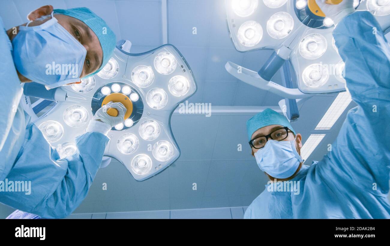 Low Angle Shot POV Patient View: Two Professional Surgeons Turning on ...