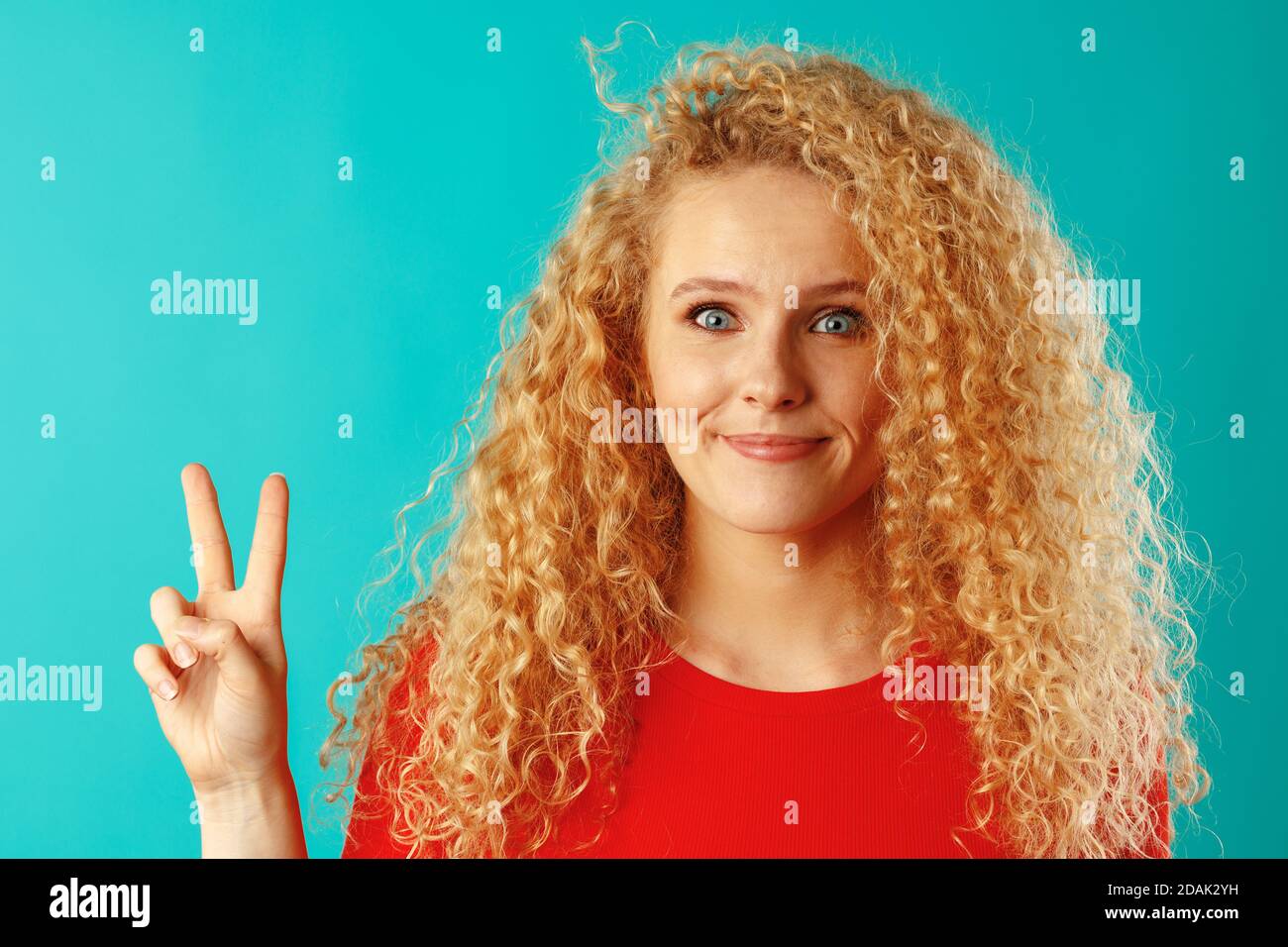 Young happy smiling woman showing victory sign Stock Photo - Alamy