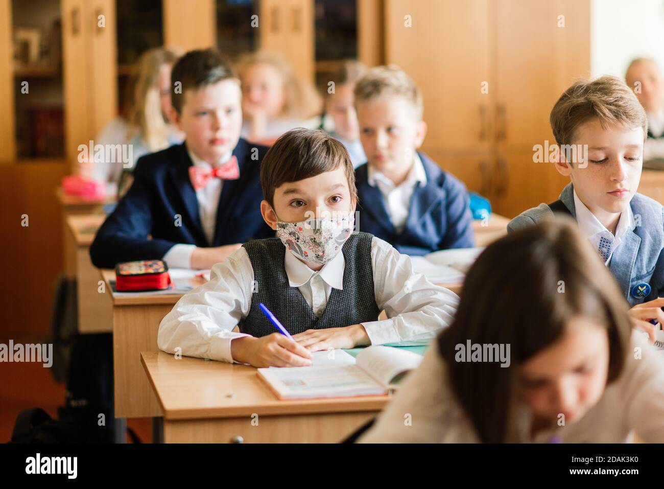 Elementary schoolchildren writing in books in classroom Stock Photo - Alamy