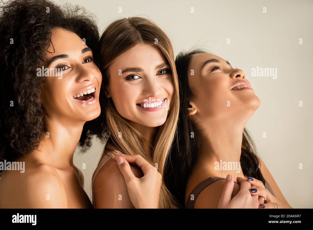 young multicultural models looking at camera and laughing isolated on ...