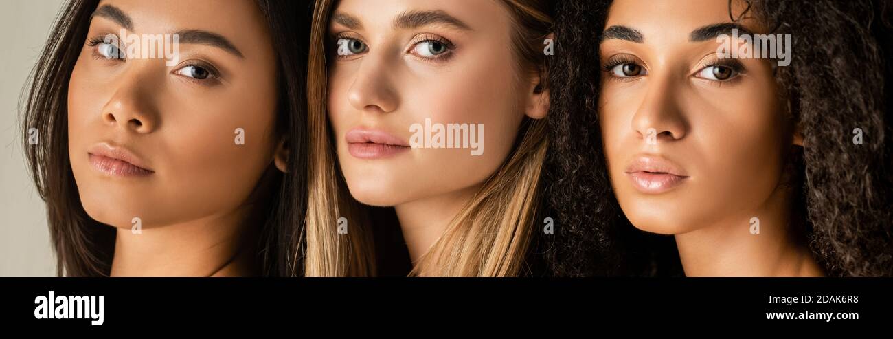 young multicultural models looking at camera isolated on white, banner ...