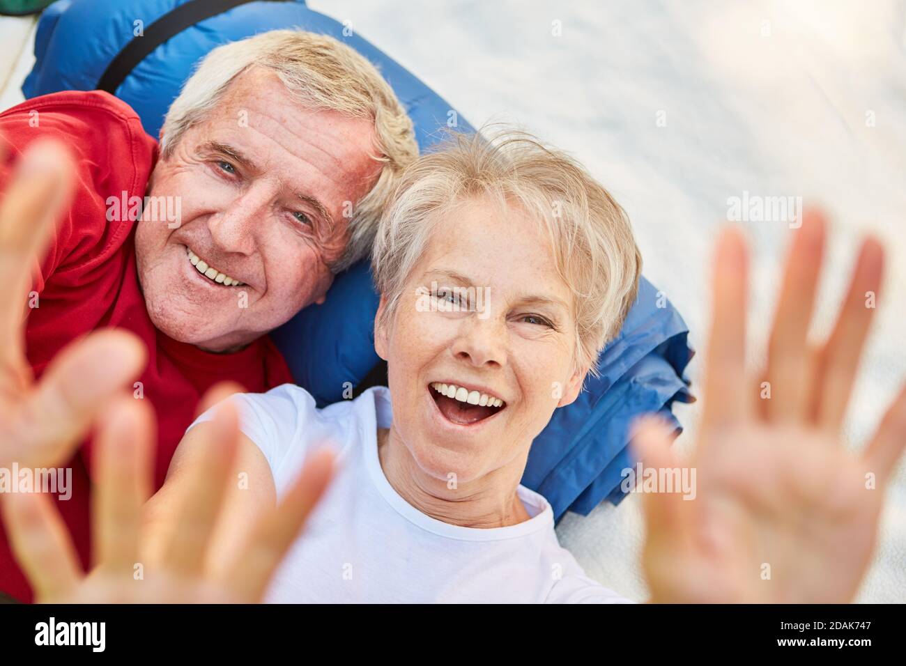 Cheerful retired senior couple is having fun camping and waving at the ...