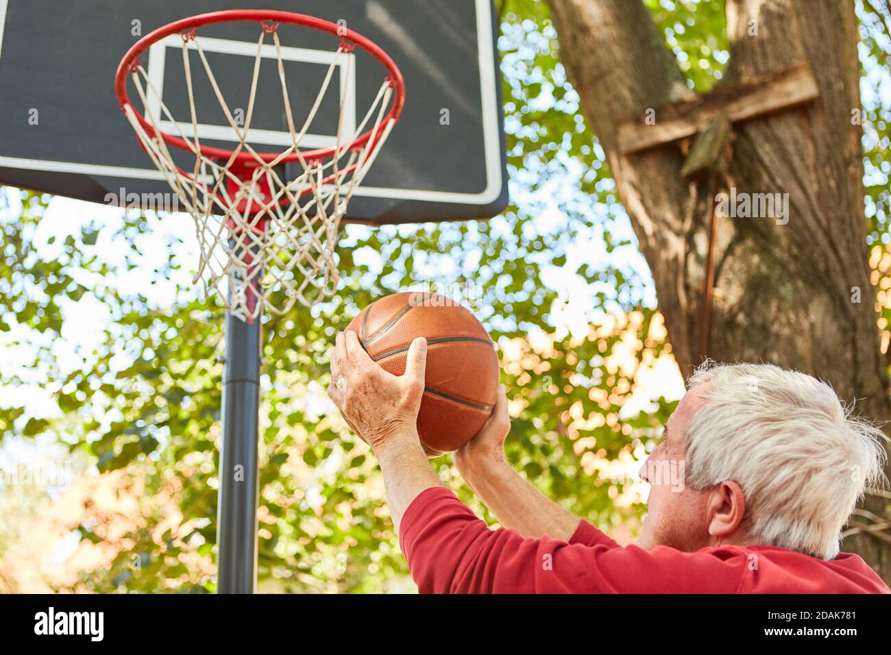Active senior playing basketball with ball while throwing in front of ...