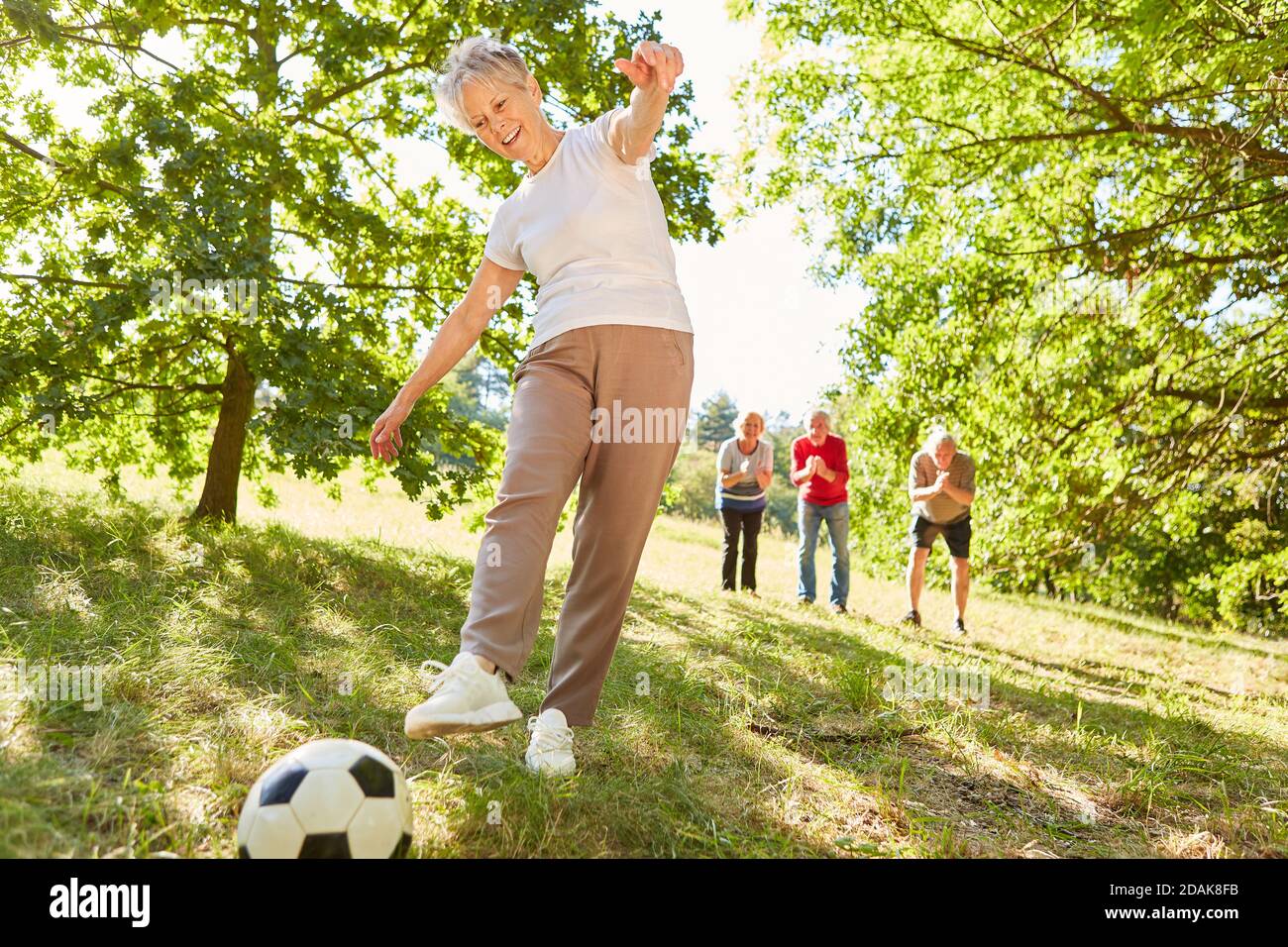 Active and vital senior citizen playing soccer on a meadow in the park ...