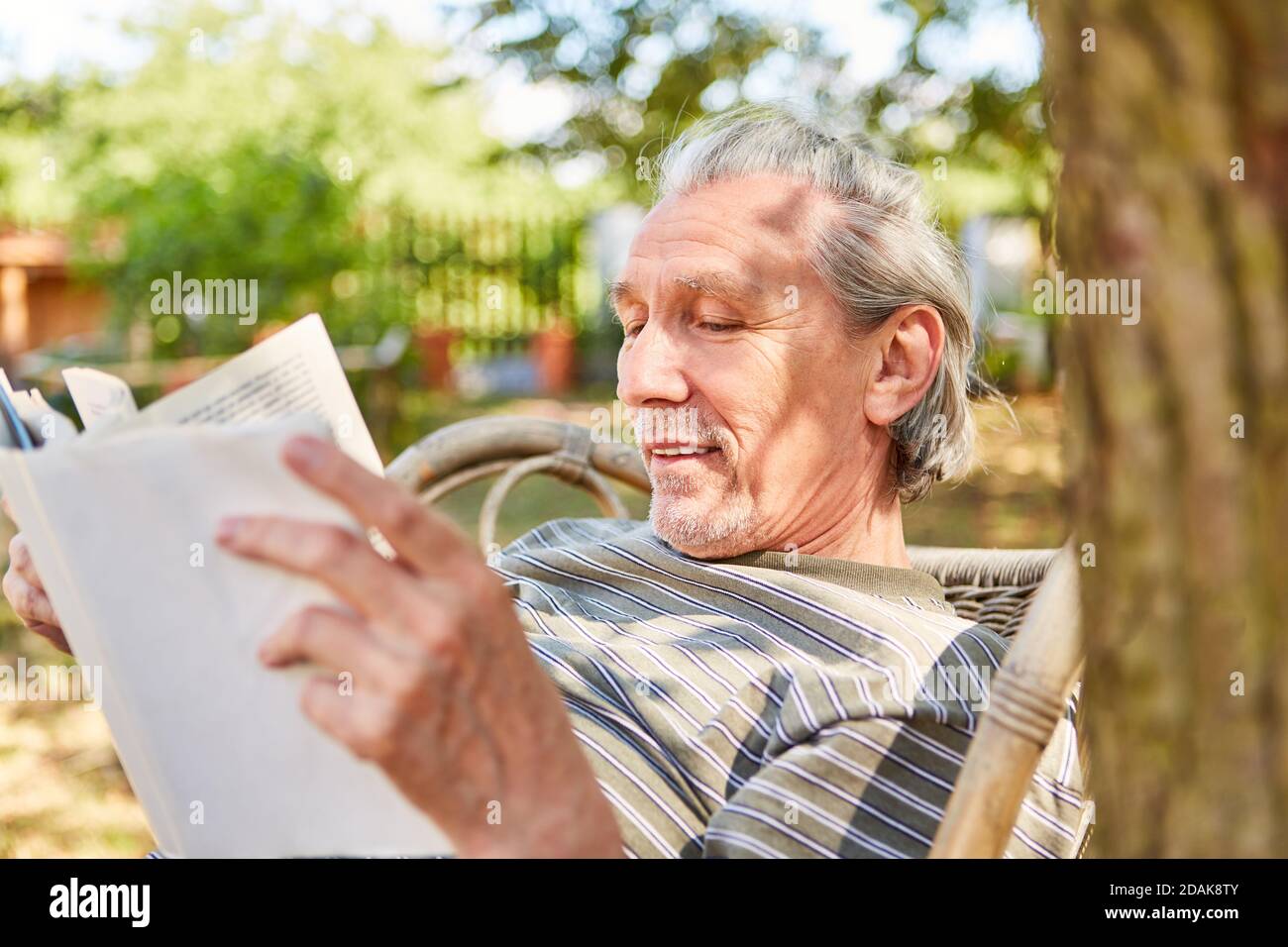 Happy senior reading book in garden in summer enjoying retirement Stock ...