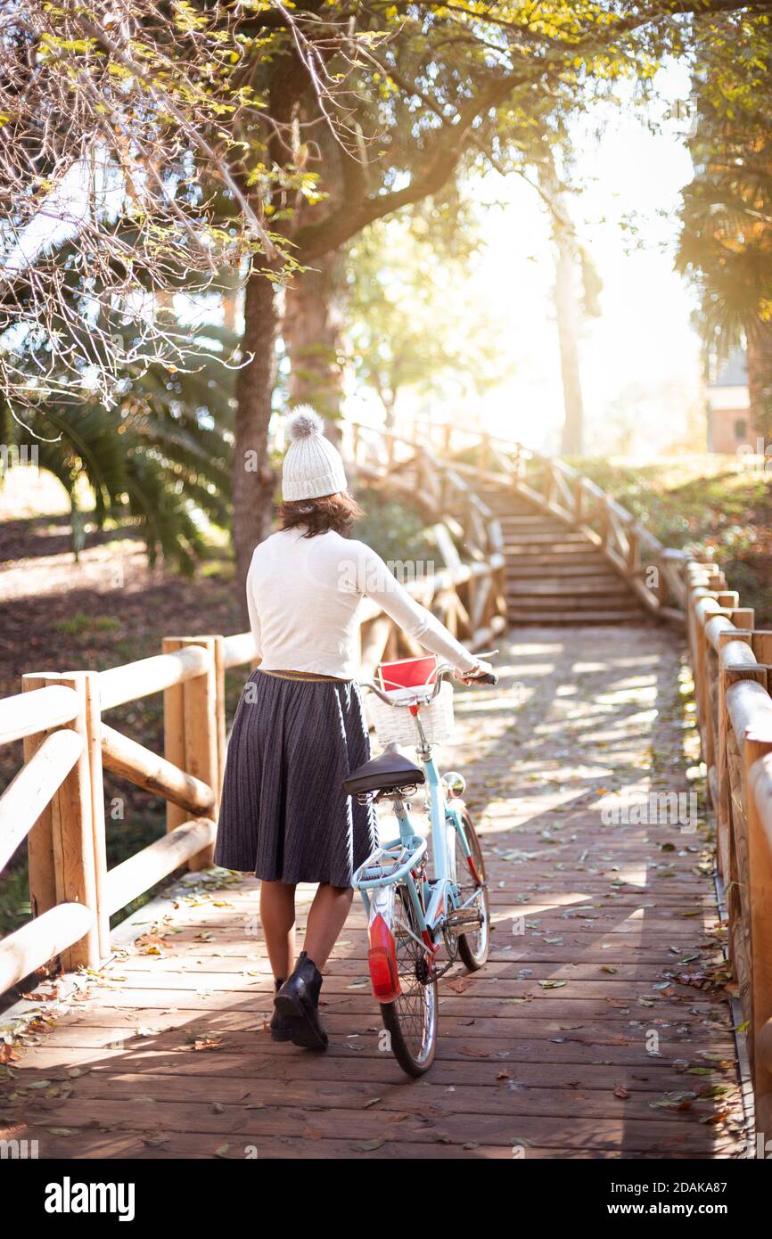 Back view of girl walking in the park with her bike. Autumn season ...
