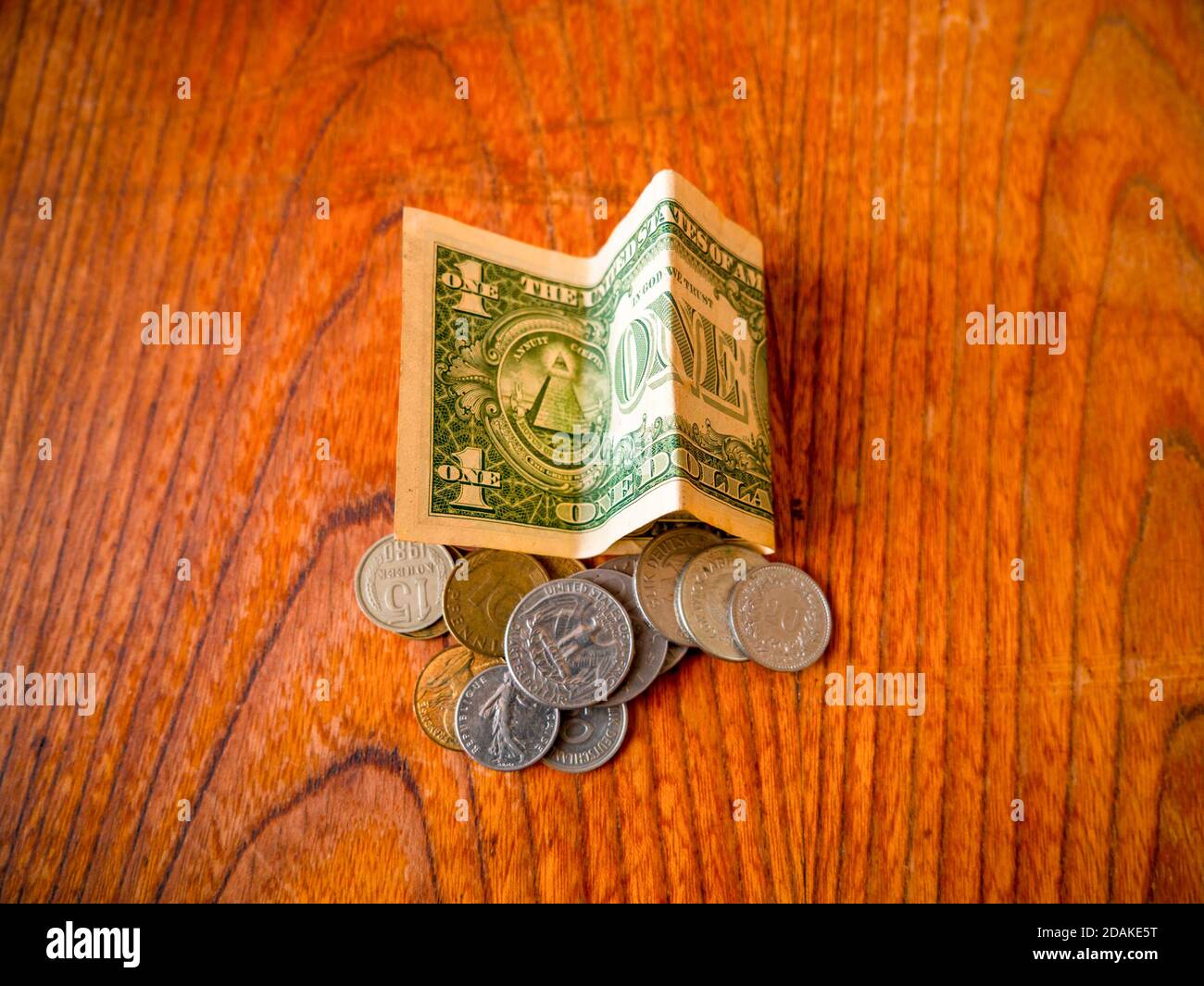 Folded One US dollar banknote and coins of different countries on a ...