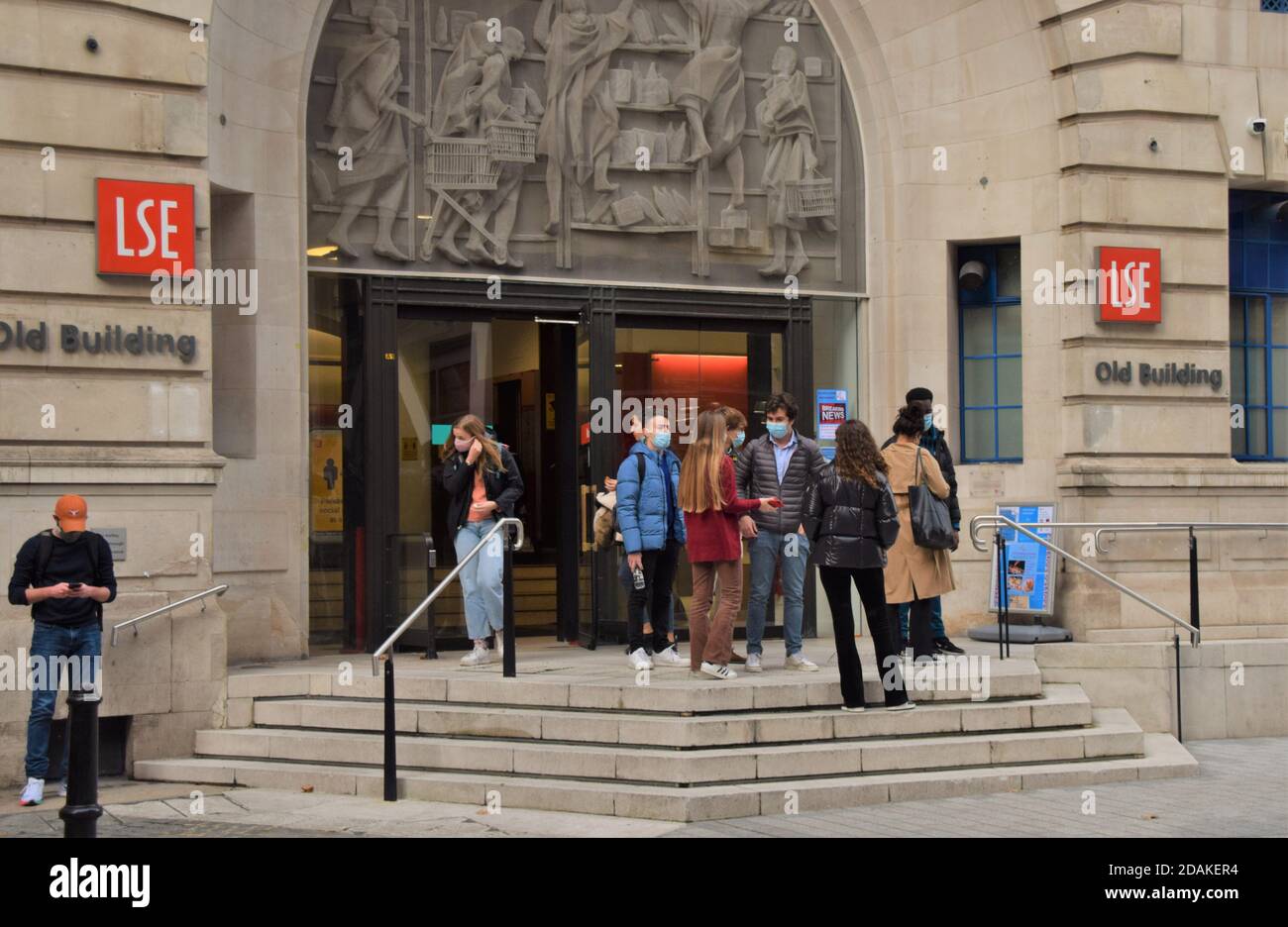 Students wearing protective face masks stand outside the LSE Old ...