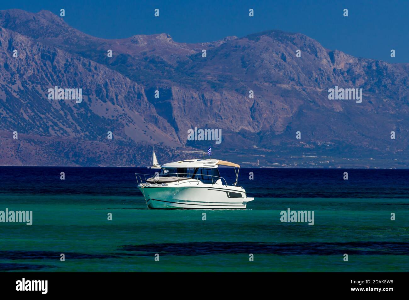 Small modern boat on the clear Aegean Sea with a towering mountainous ...