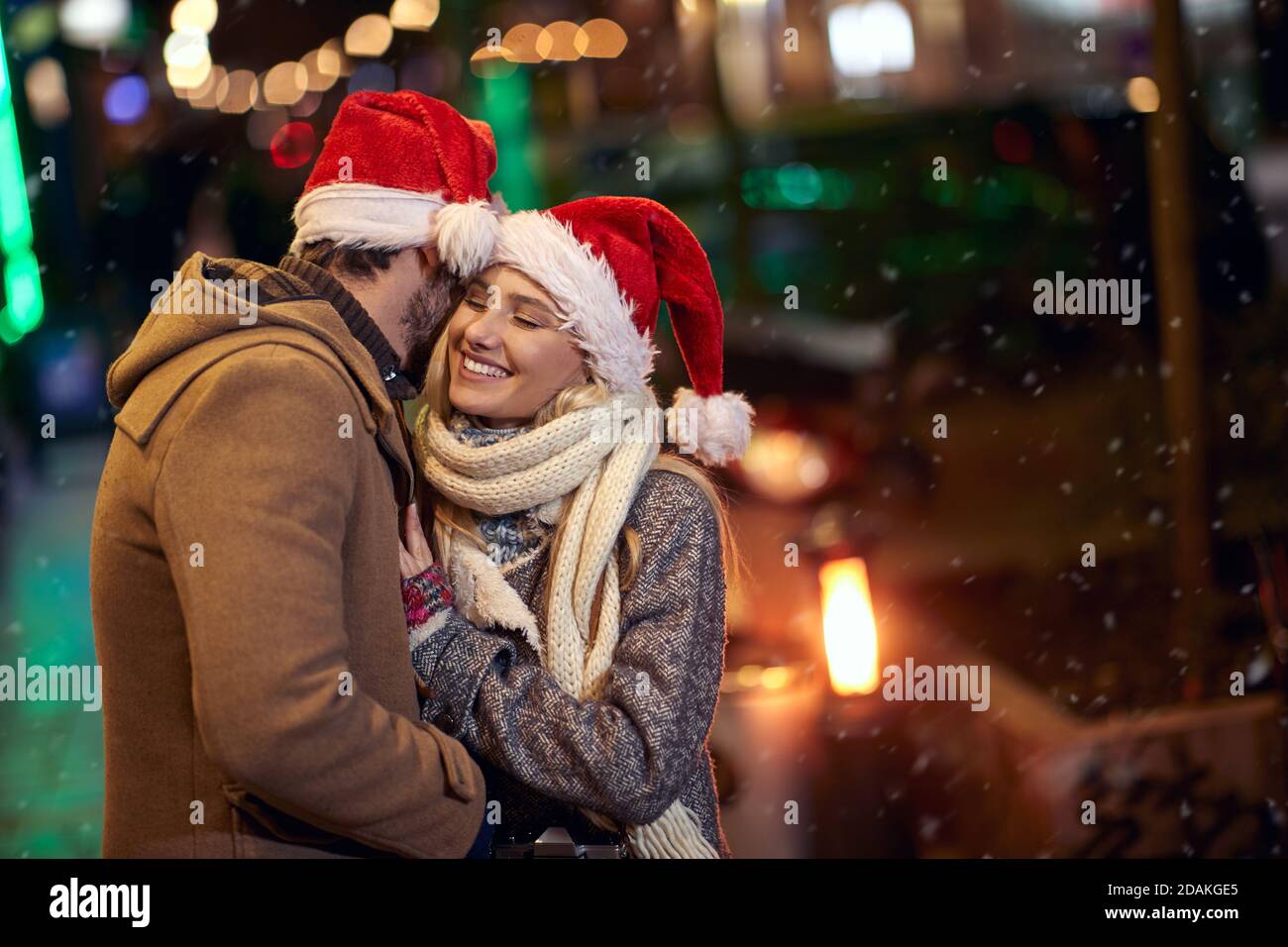 A young couple with Santa caps walking the city on a cold night ...
