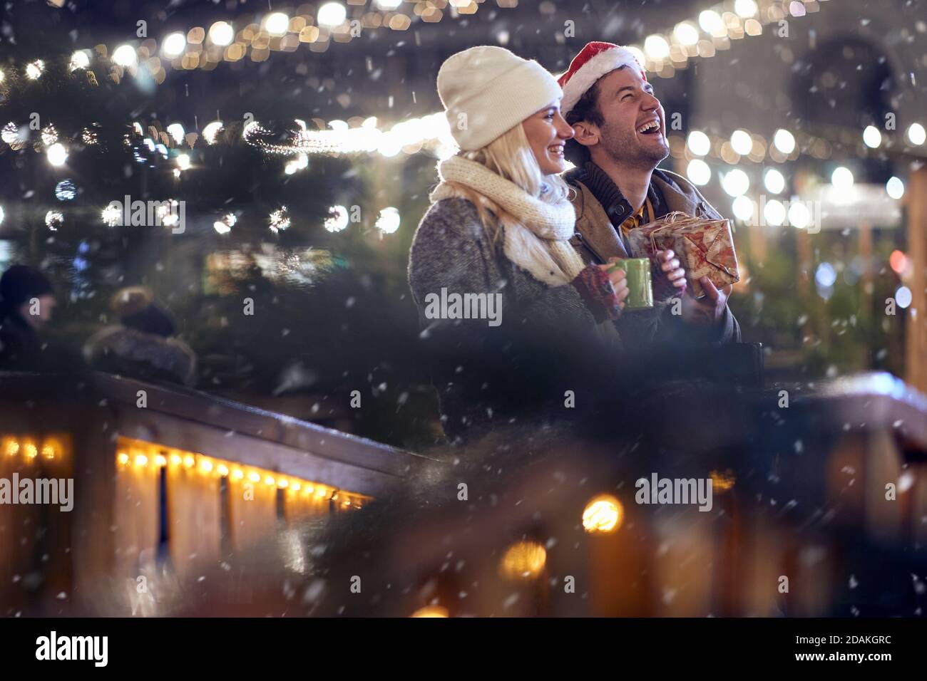 A young couple in love enjoying snowfall in a magical night at ...