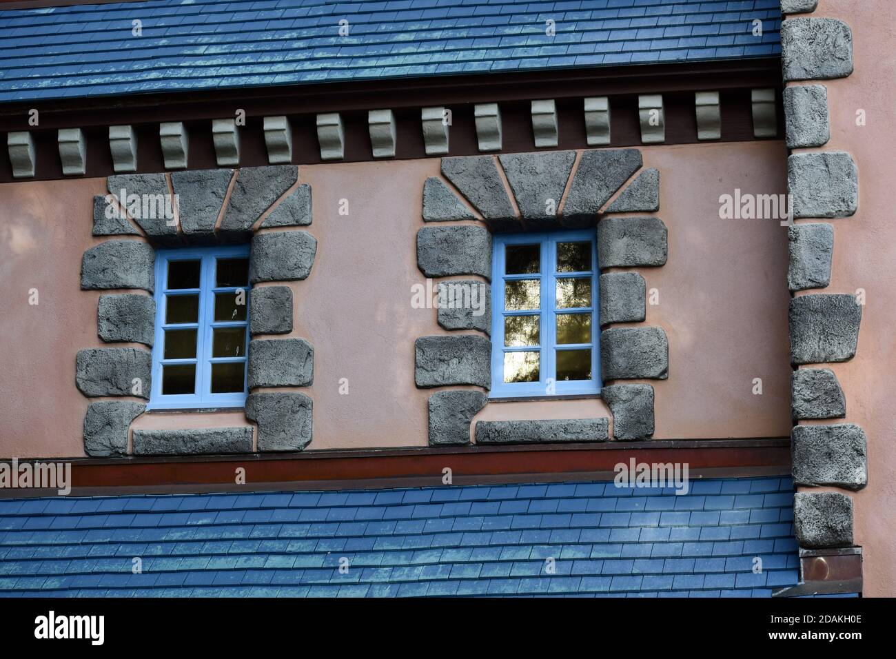Blue glass windows surrounded by partitioned bricks on a pink wall ...