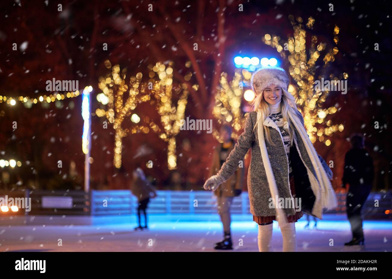 A young girl enjoying skating at ice rink on a beautiful magical night ...