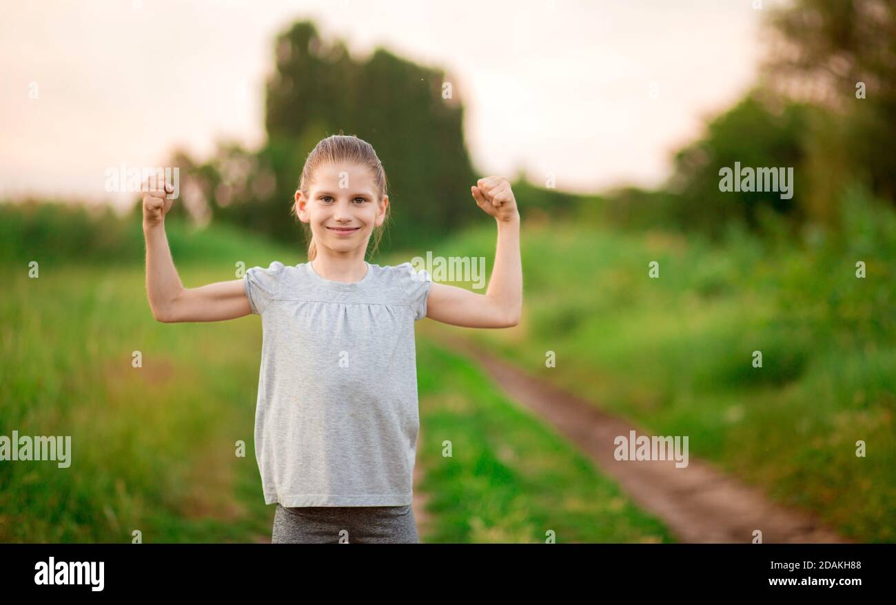 Child cute girl show biceps gesture of power and strength outdoor. Feel ...