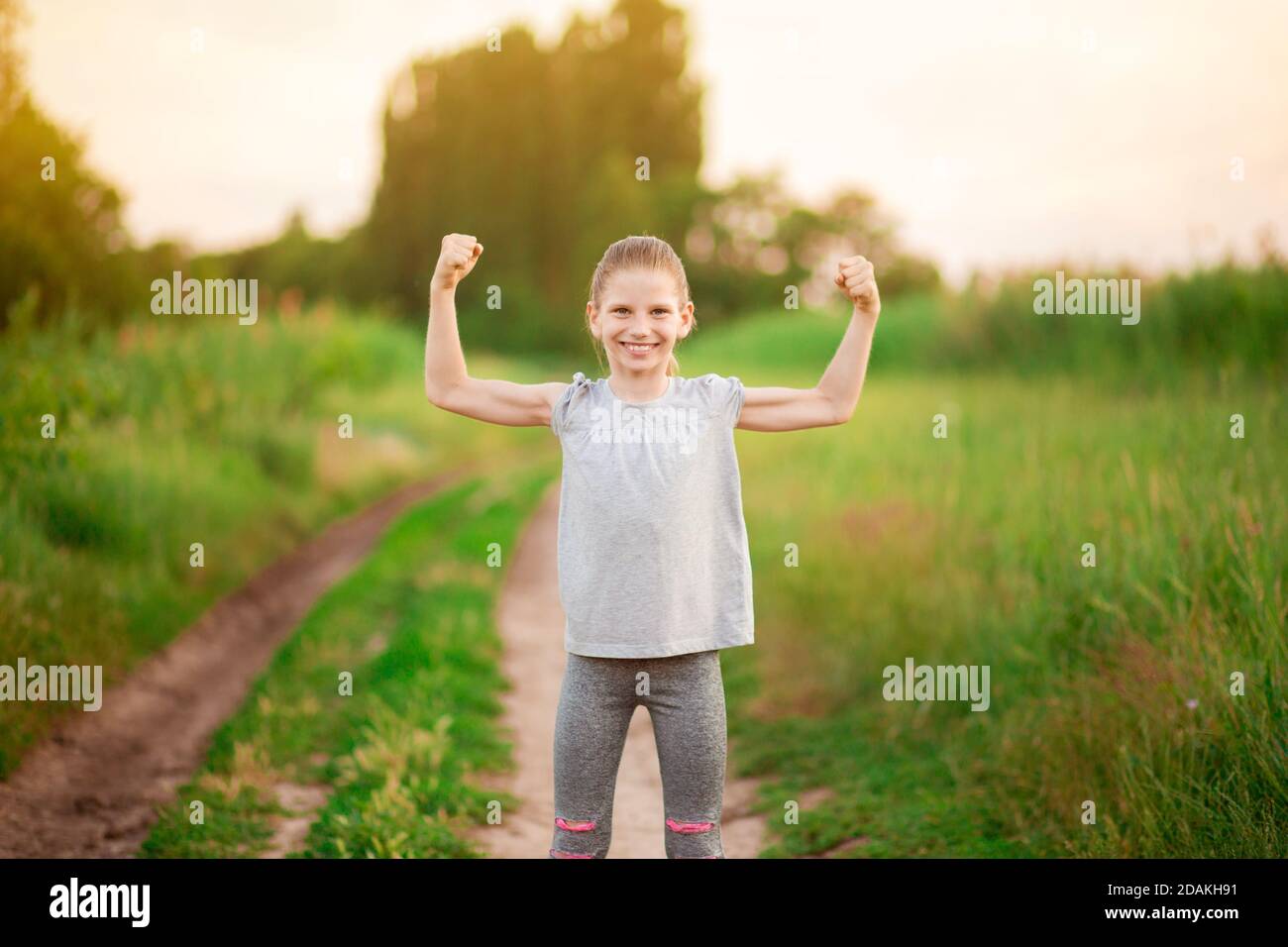 Child cute girl show biceps gesture of power and strength outdoor. Feel ...