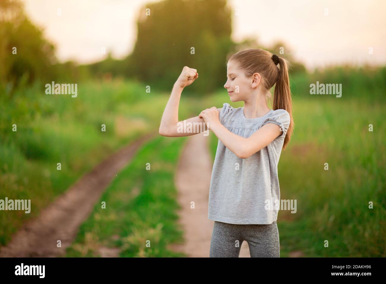 Child cute girl show biceps gesture of power and strength outdoor. Feel ...
