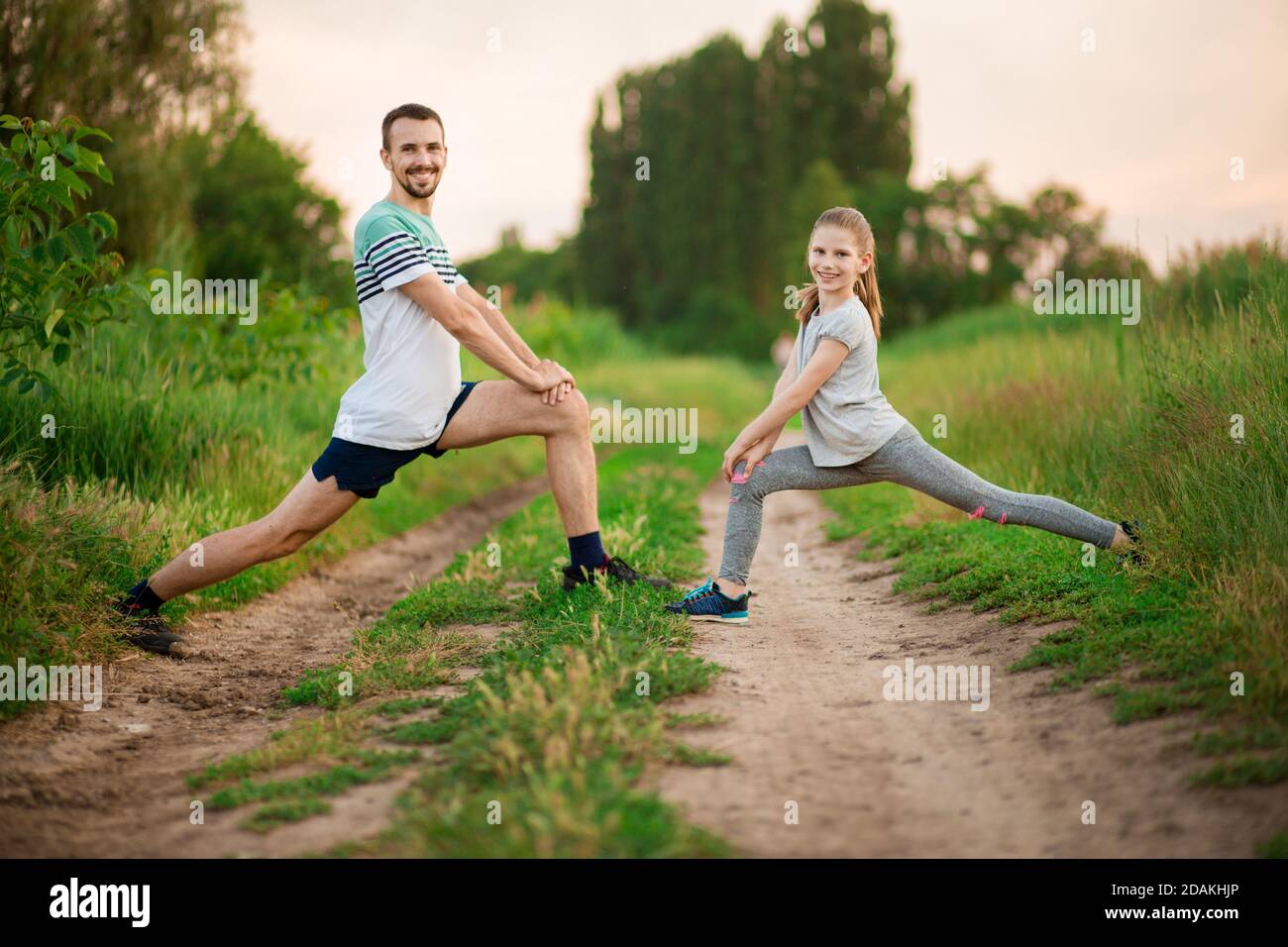 Athletic young father and little daughter do exercises in stadium ...