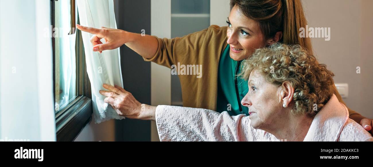 Caregiver showing the view through the window to elderly patient Stock ...