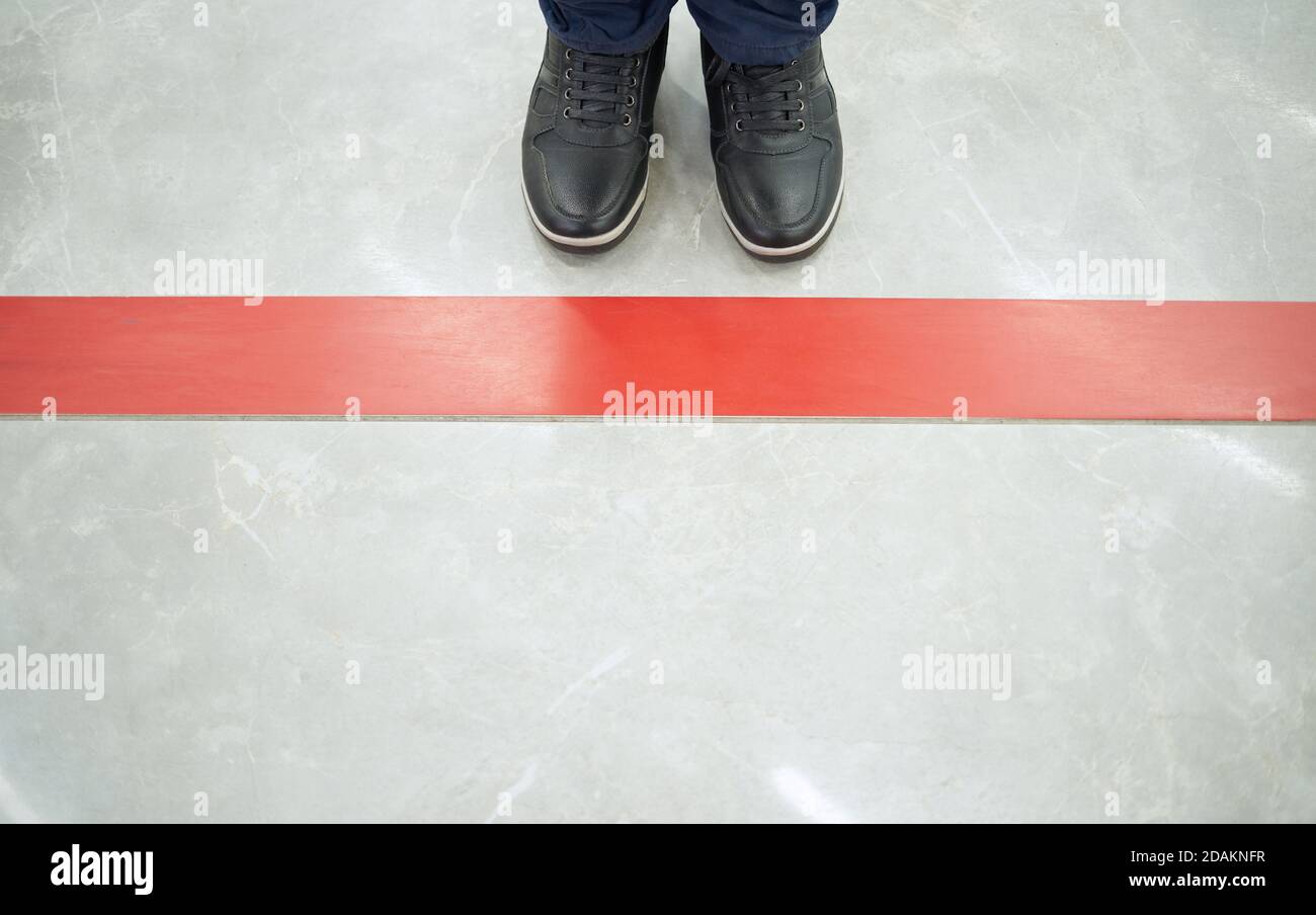 A person stands at the red line on the floor in a shopping center ...