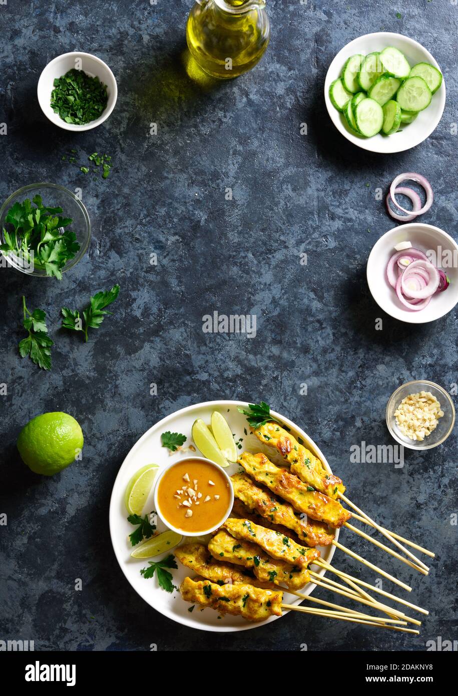 Frame of chicken satay with peanut sauce and ingredients on blue stone ...