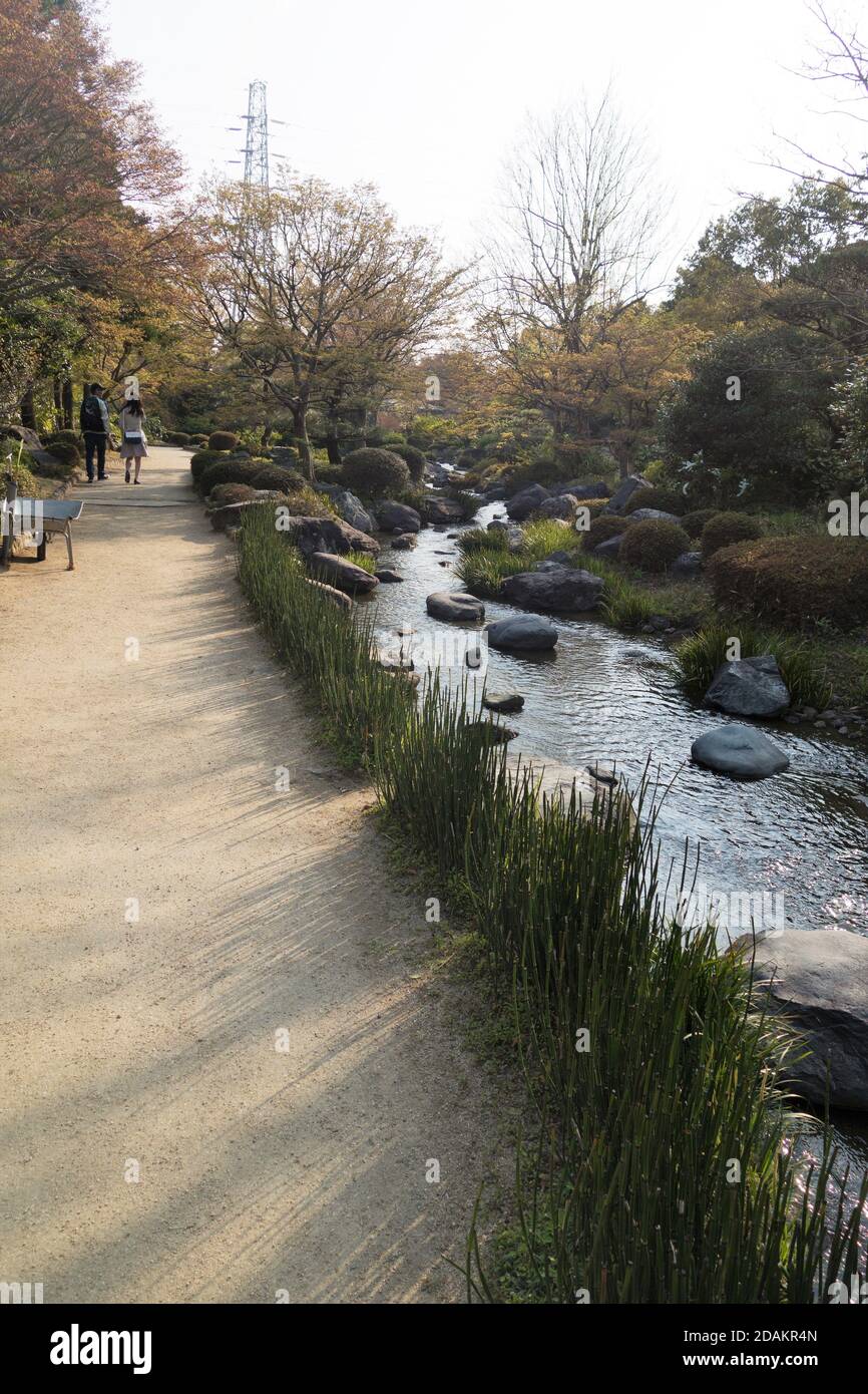 A man and woman walking a path next to a stream in Daisen Park Japanese ...