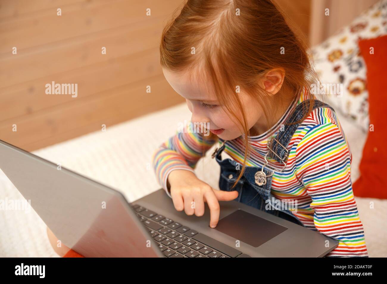 A little girl looks at the computer with different emotions. Girl plays ...