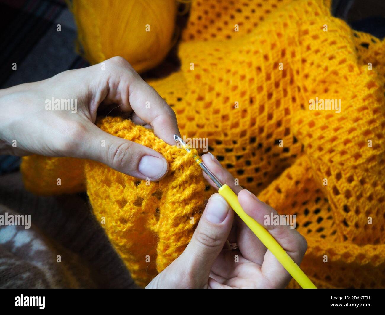 Crochet. Woman crochet yellow yarn on the dark background. Close-up of ...