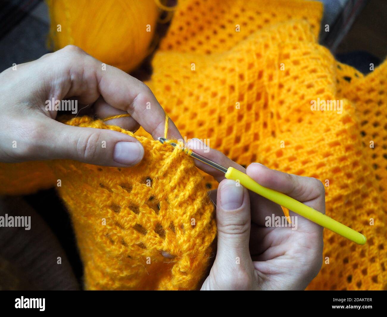 Crochet. Woman crochet yellow yarn on the dark background. Close-up of ...