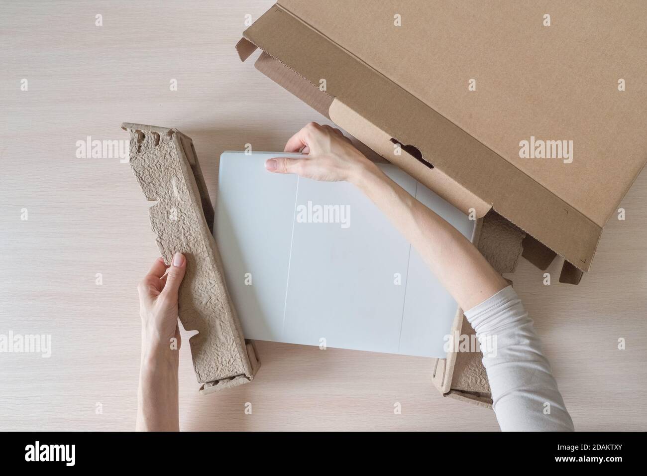 Unpacking a new laptop from a cardboard box. Hands open the box ...