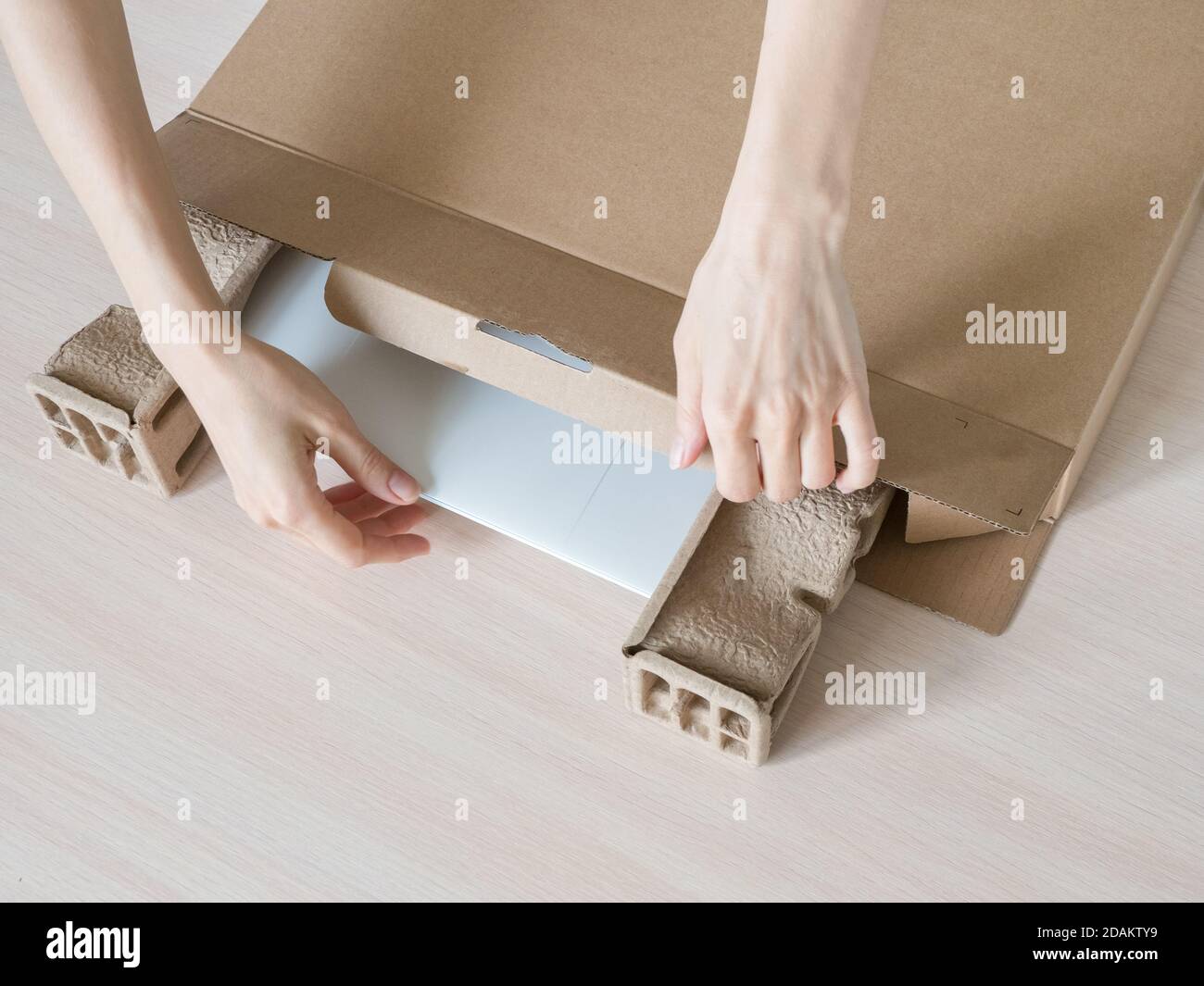 Unpacking a new laptop from a cardboard box. Hands open the box ...