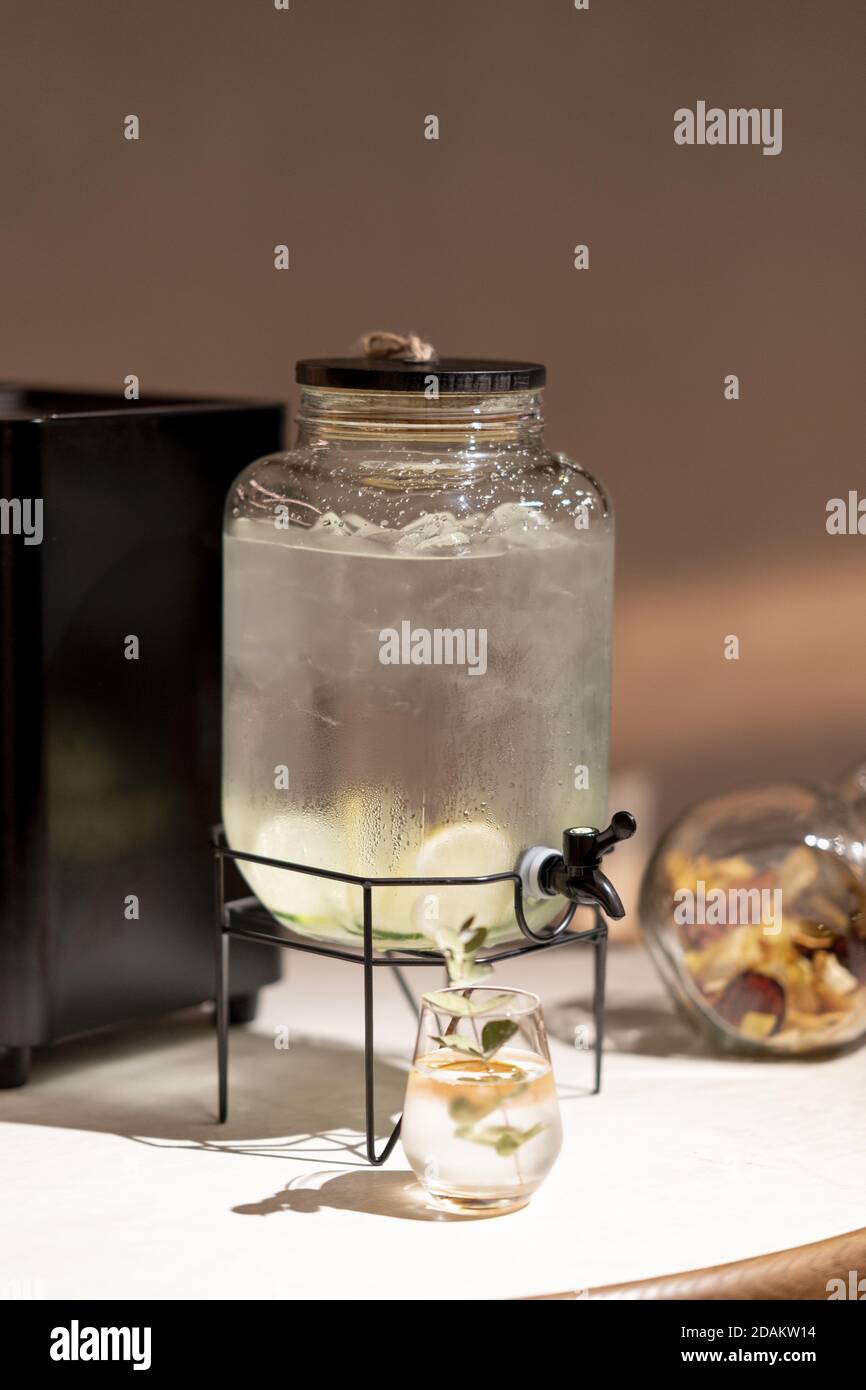 Vertical shot of a container of water with ice and lemon on the ...