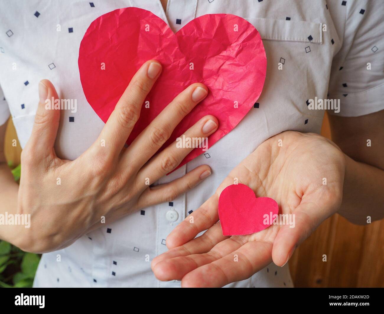 Donated heart. Large and small red heart in his hand Stock Photo - Alamy