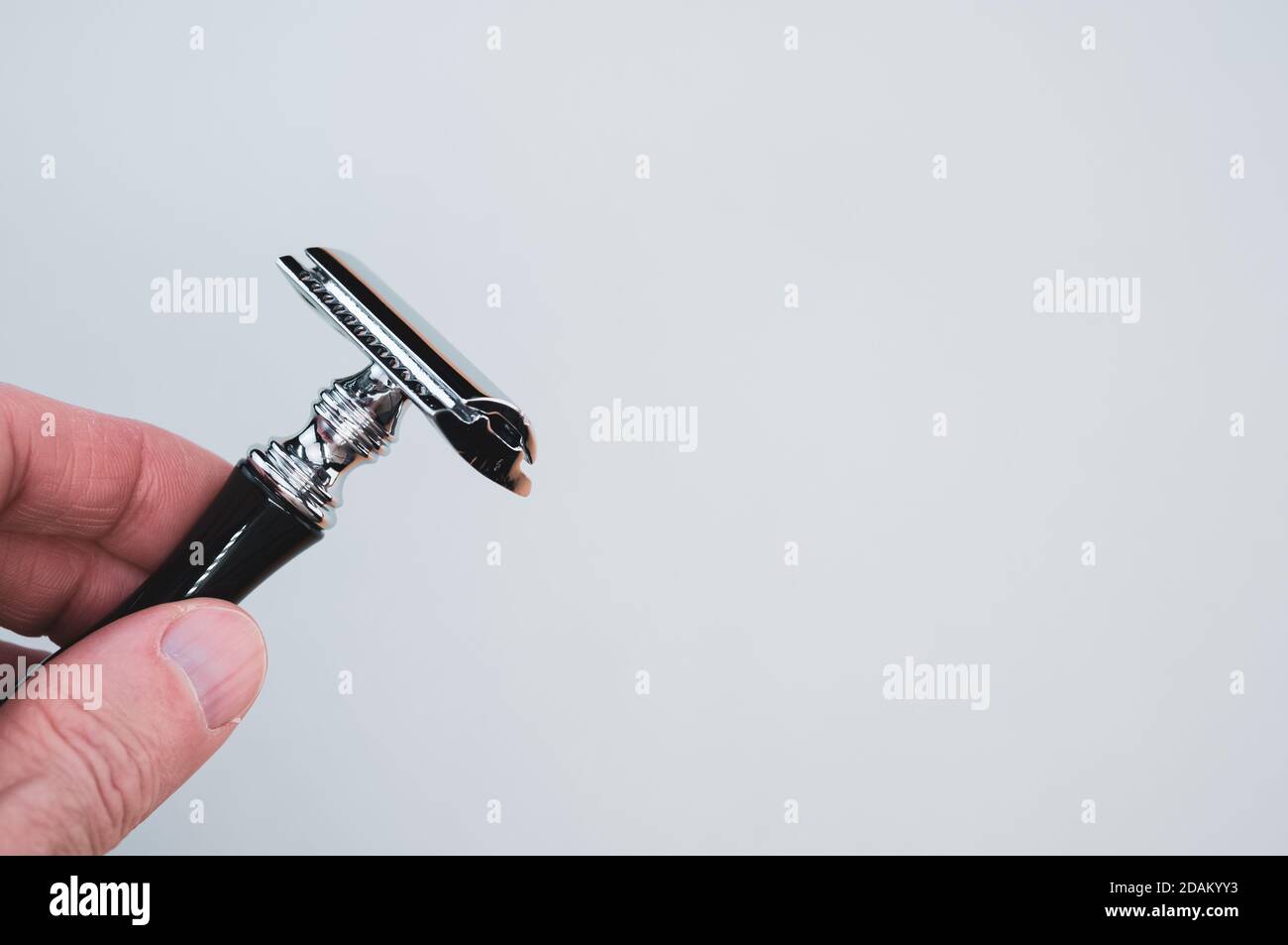 Hand holding a shaving razor on a light green background Stock Photo ...