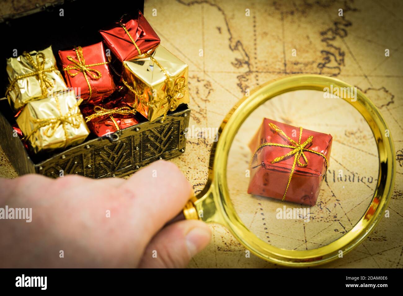 the treasure hunt. A hand with a magnifying glass above a chest full of ...