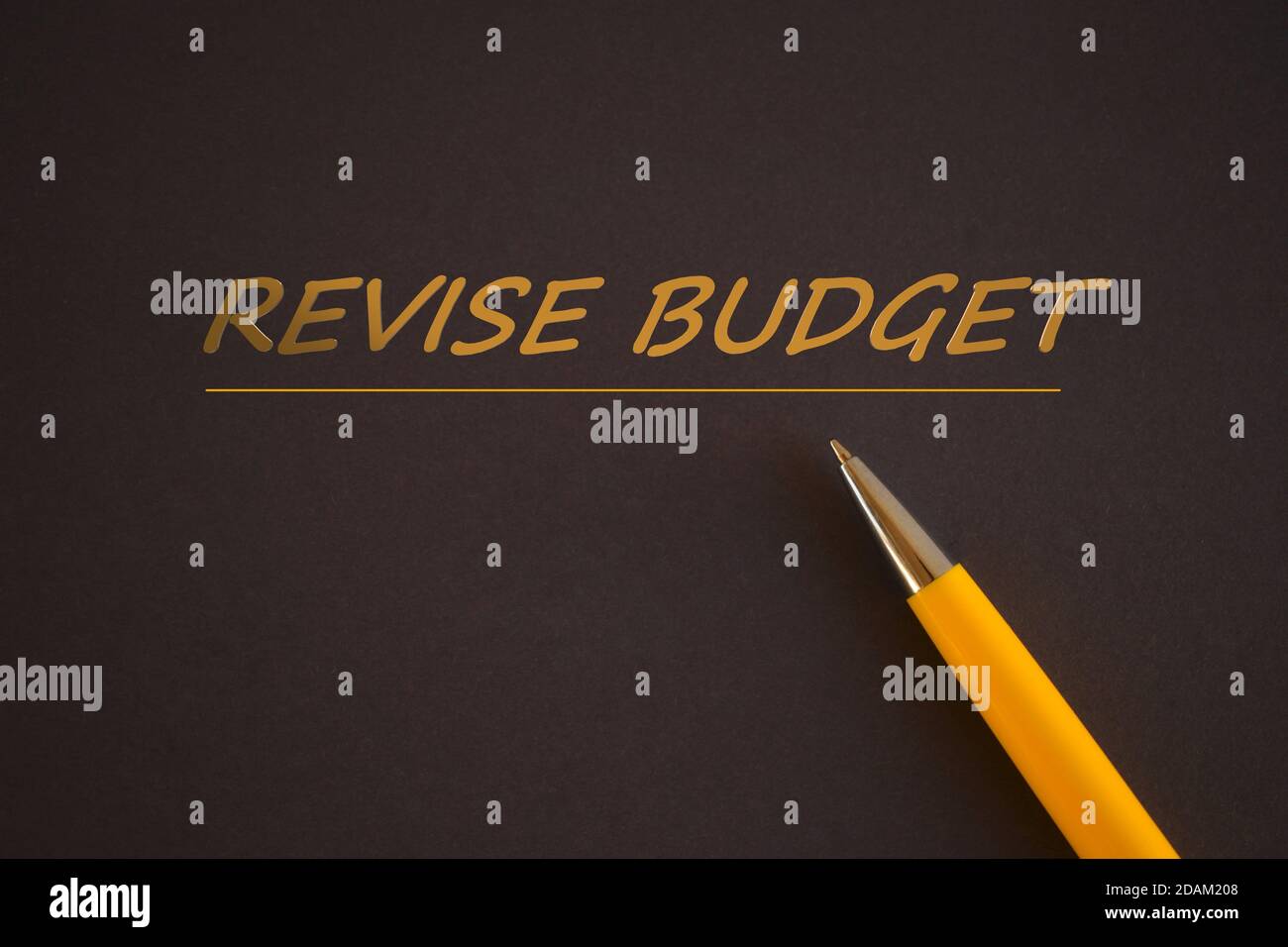 REVISE BUDGET text on dark background.Orange Pen and orange text ...