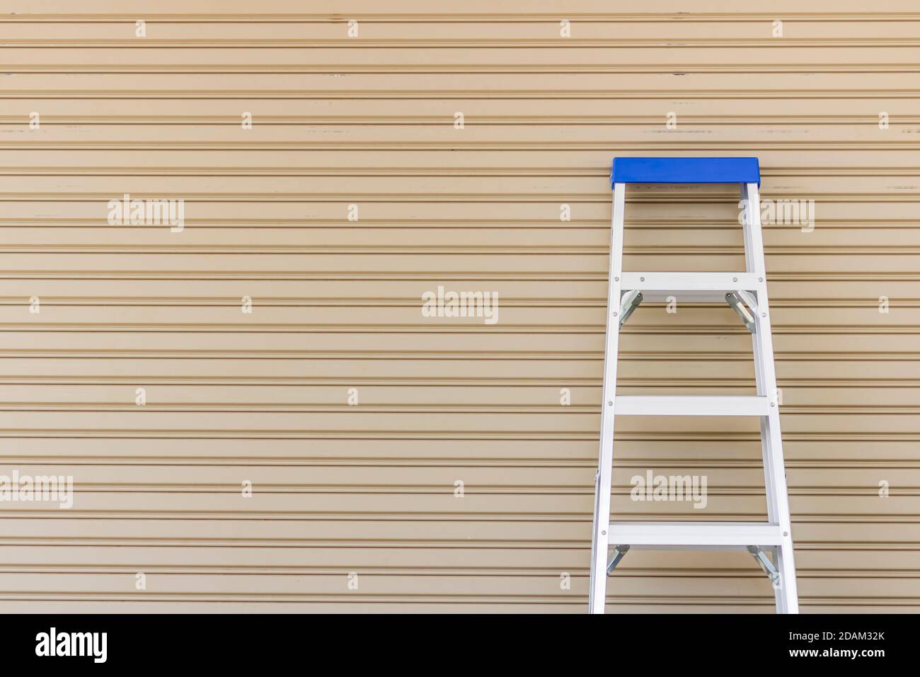 An aluminum foldable ladder leaning on the metal wall Stock Photo - Alamy